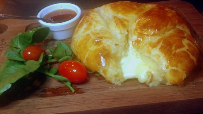 Um folhado de brie com queijo derretido escorrendo. Na Cantina do Délio